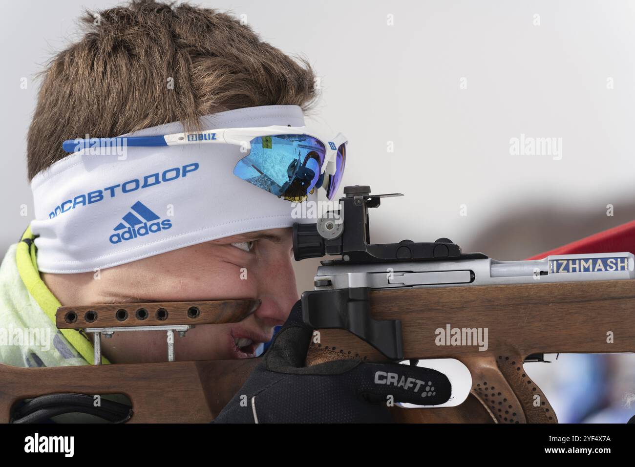Close-up view sportsman biathlete aiming rifle shooting in prone ...