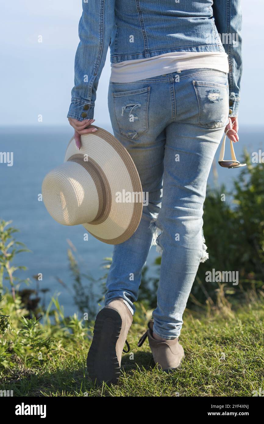 Rear view below waist on legs of hipster female in blue jeans and boots ...