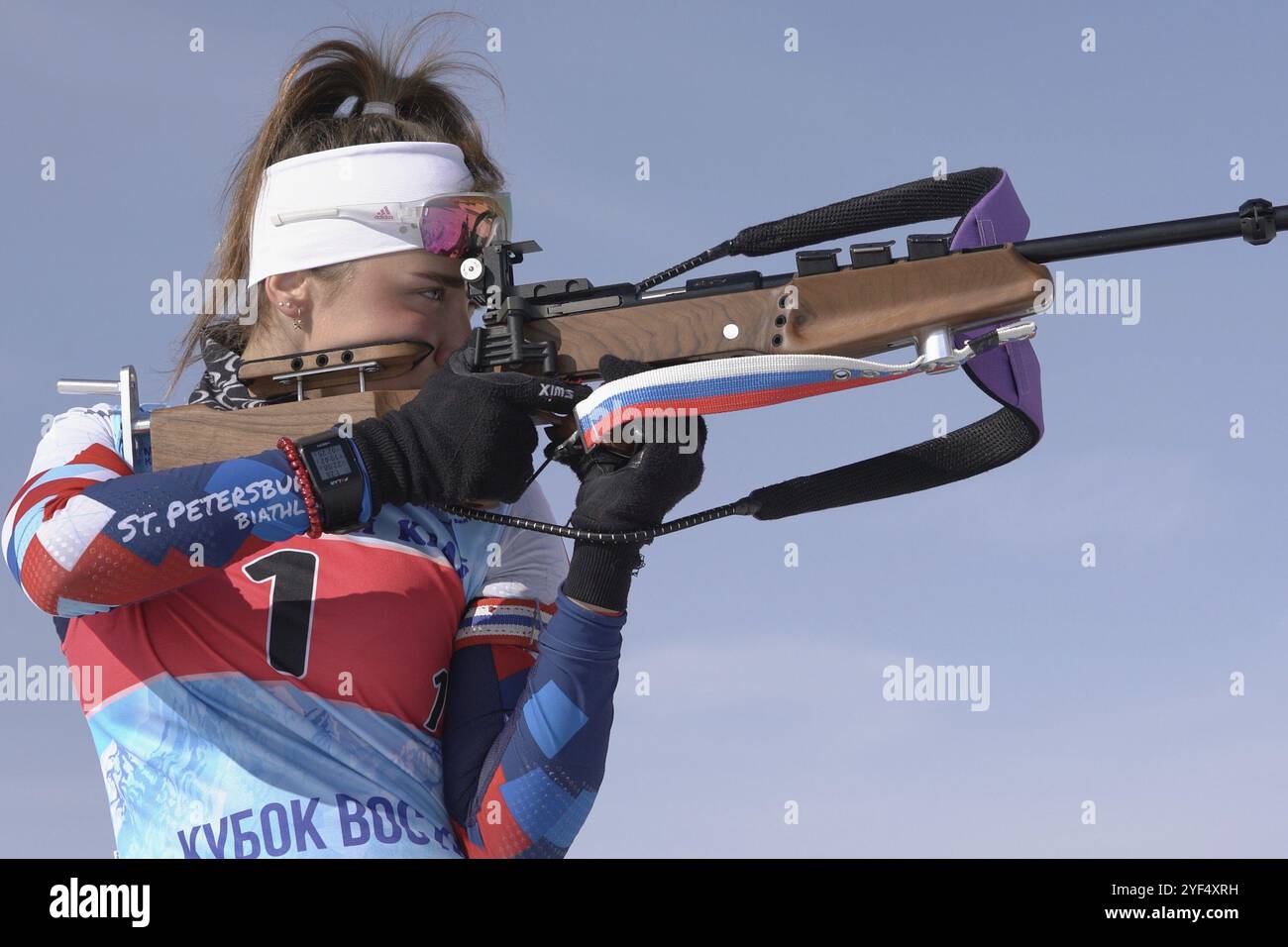 Sportswoman biathlete aiming, rifle shooting standing position ...