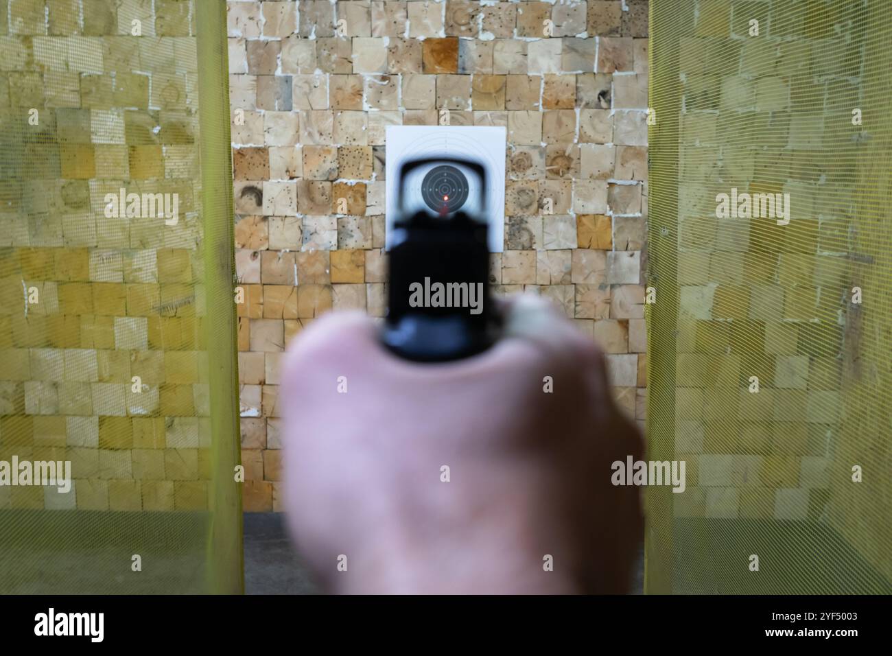 Shooting a pistol with a red dot sight at a paper target at an indoor ...