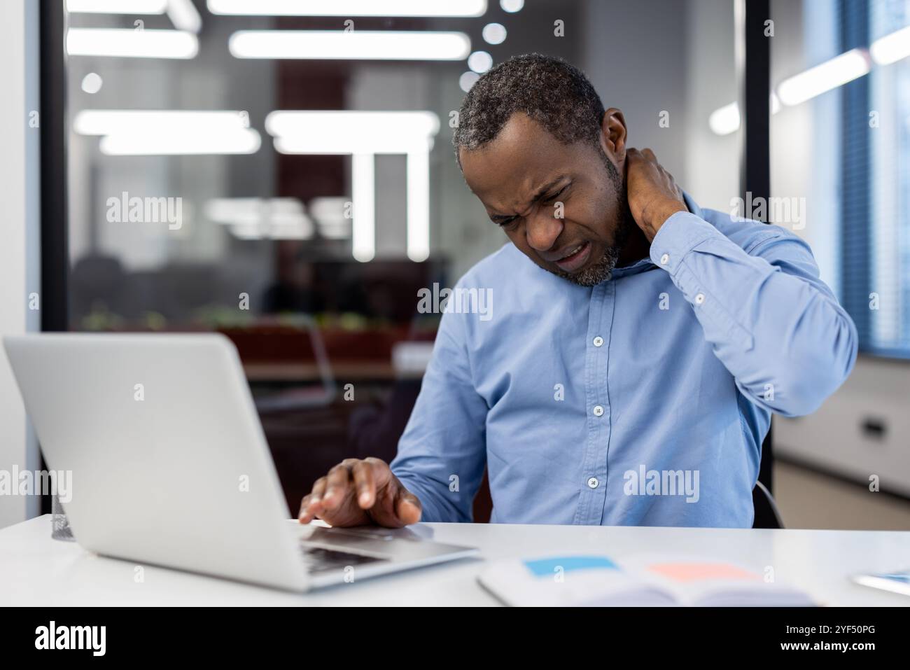Mature african american businessman experiencing neck pain at desk ...