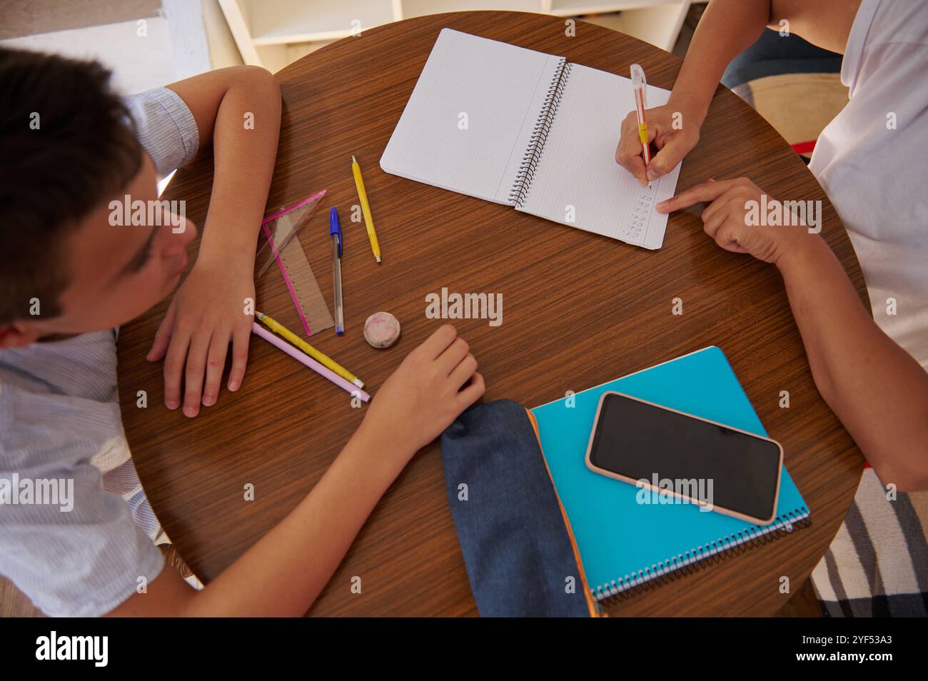 Two students work together on a homework project, using notebooks and ...