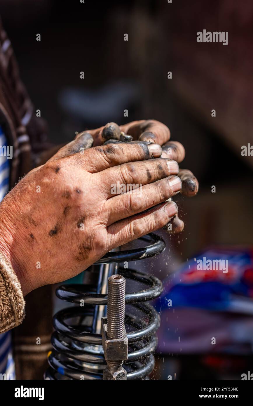 The calloused hands of a mechanic assembling compressed coil spring ...
