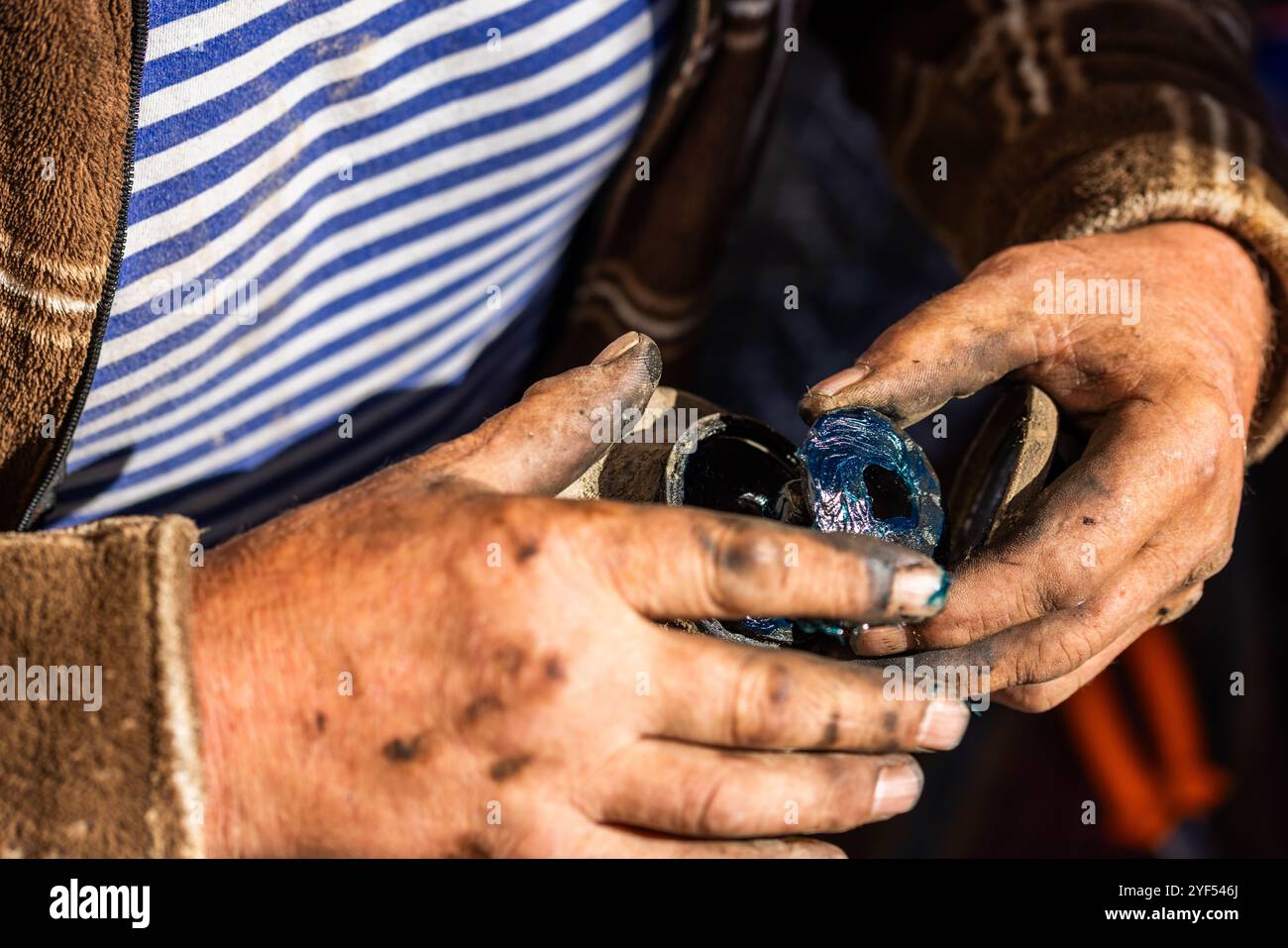The calloused hands of a mechanic assembling compressed coil spring ...