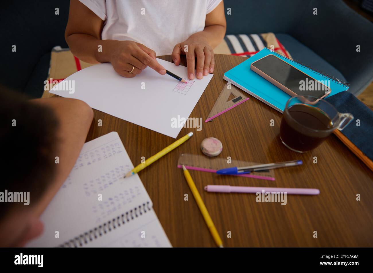 Two students work together at a home table, surrounded by notebooks ...