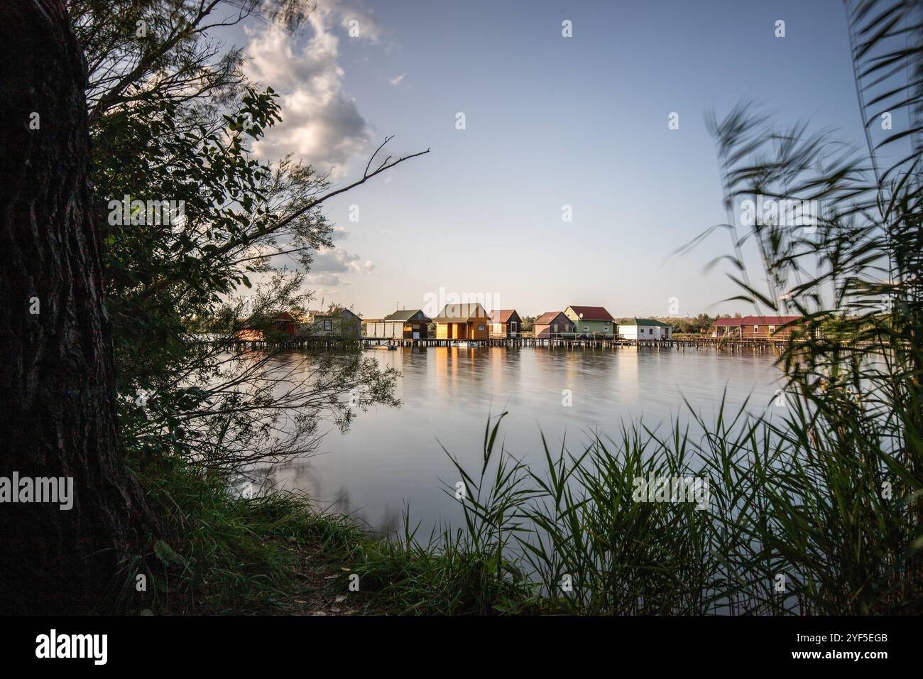 Wooden houses in the water at sunset. Long wooden walkways of the ...