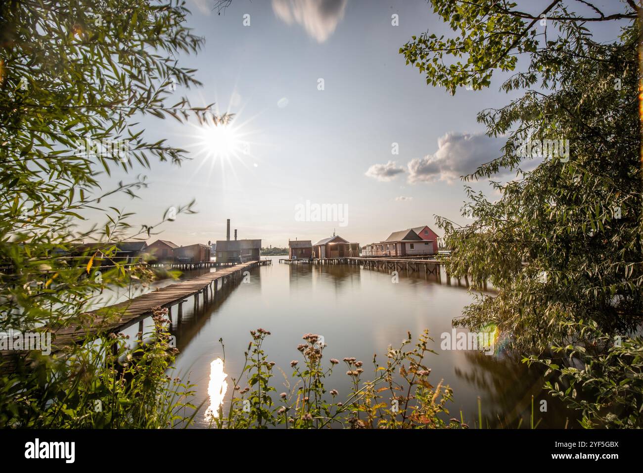 Wooden houses in the water at sunset. Long wooden walkways of the ...