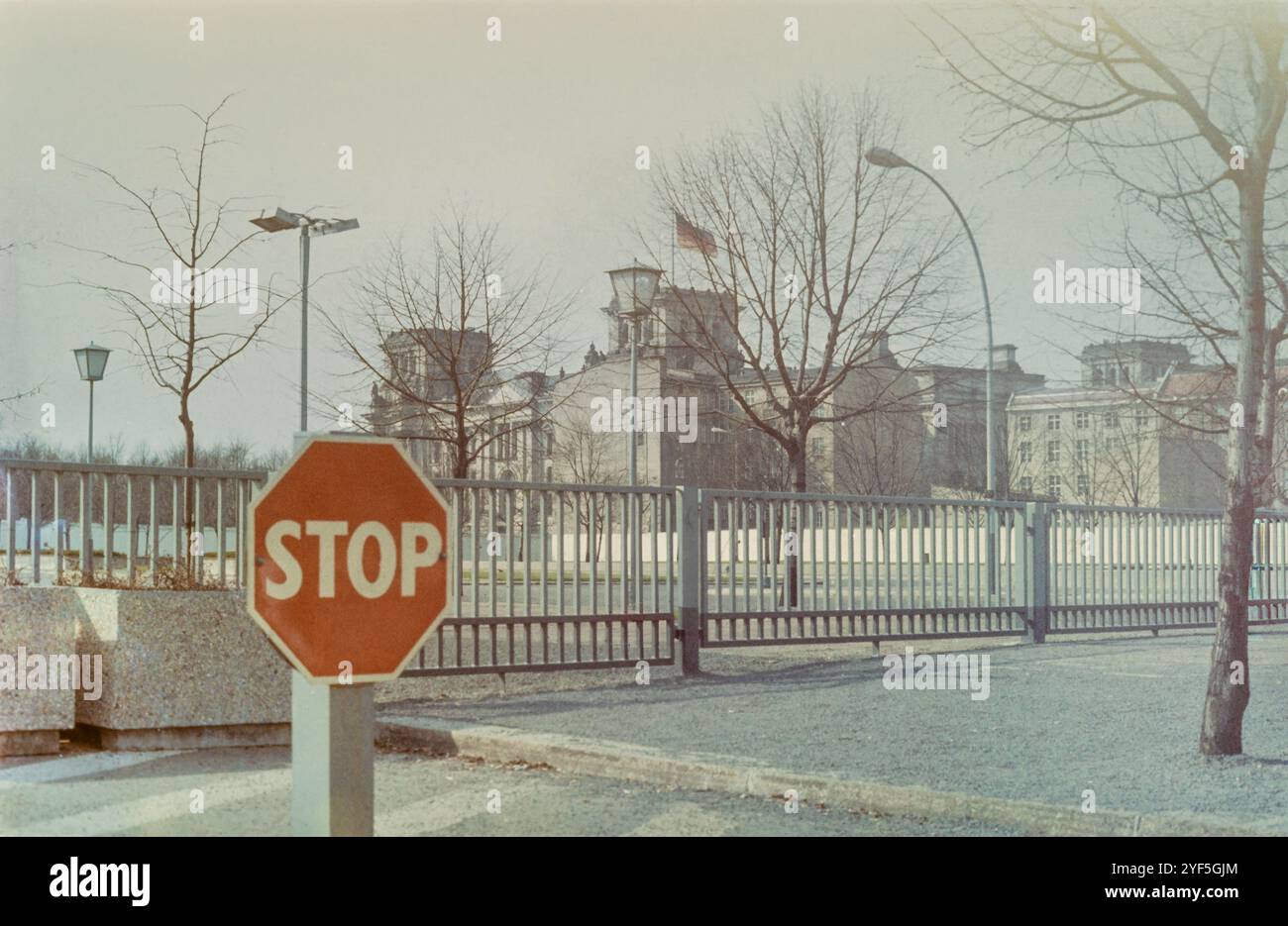 Berlin, Germany. Ca 1986. A red stop sign and a fence runs along the ...