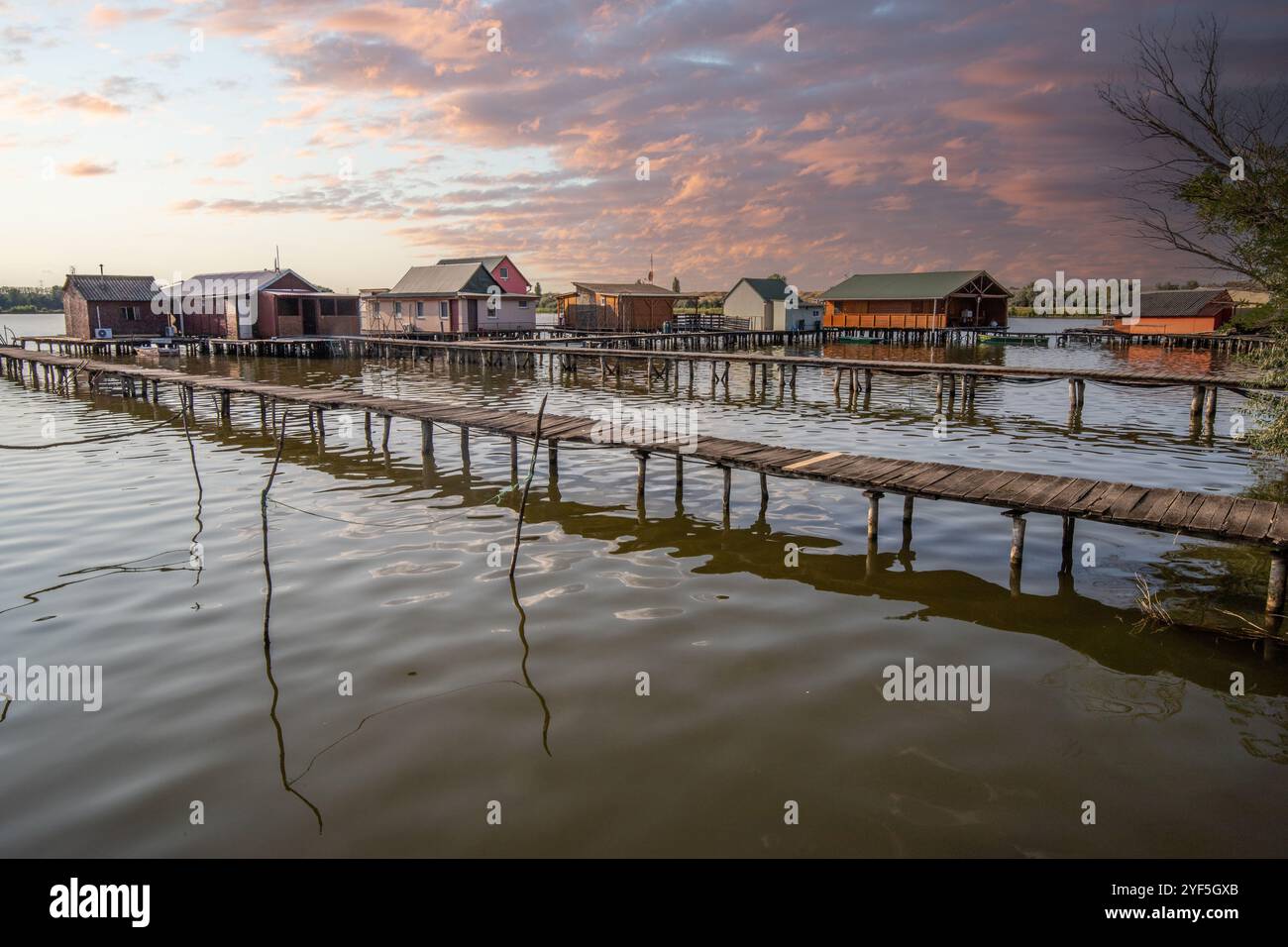 Wooden houses in the water at sunset. Long wooden walkways of the ...