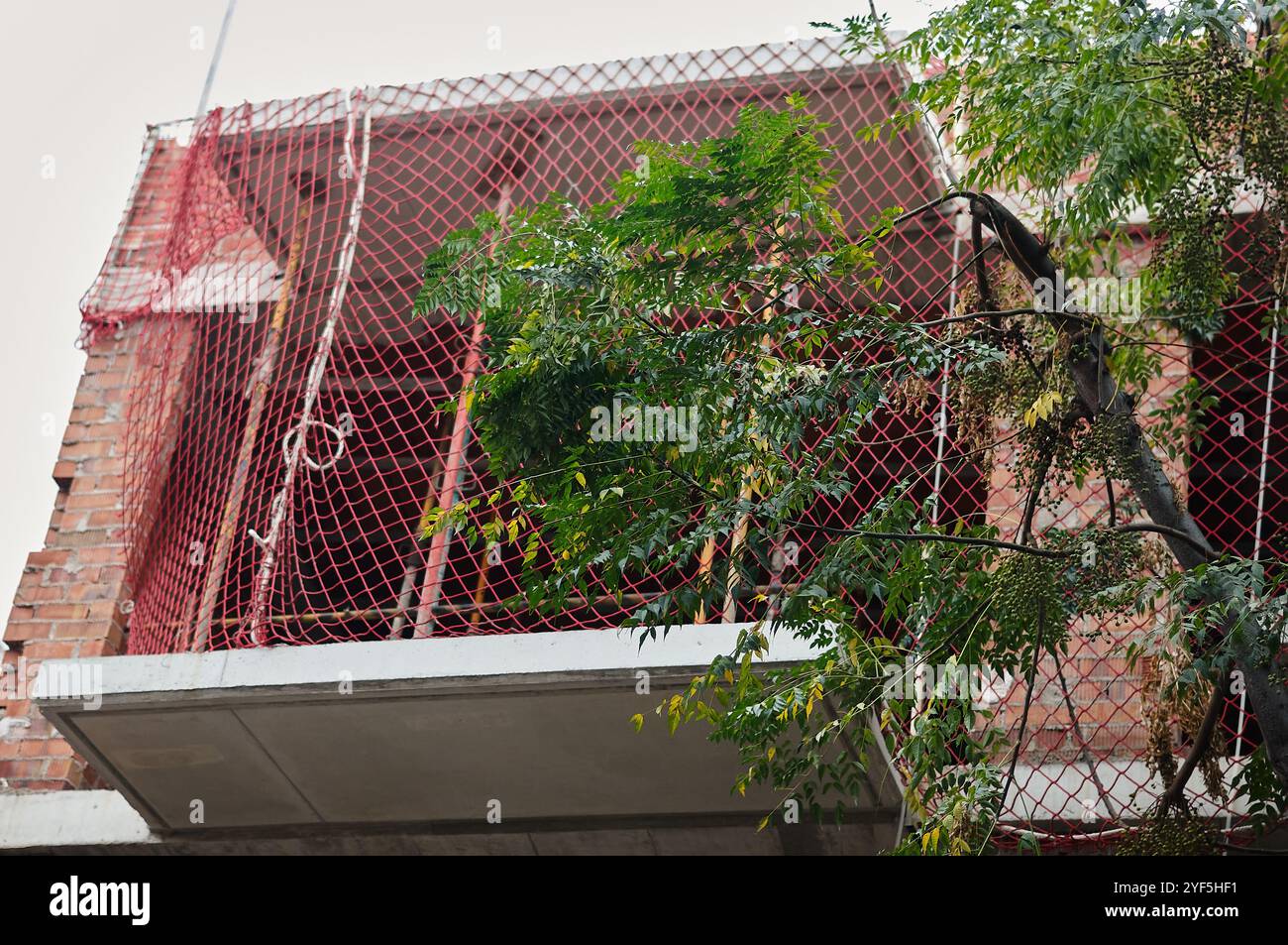 This image shows a red safety net installed on a balcony of a ...