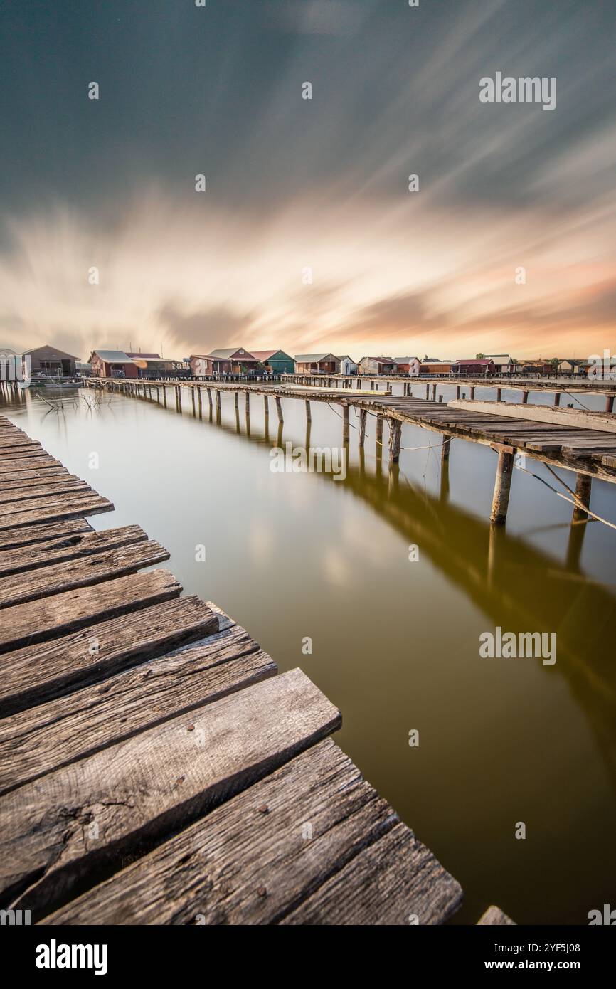 Wooden houses in the water at sunset. Long wooden walkways of the ...