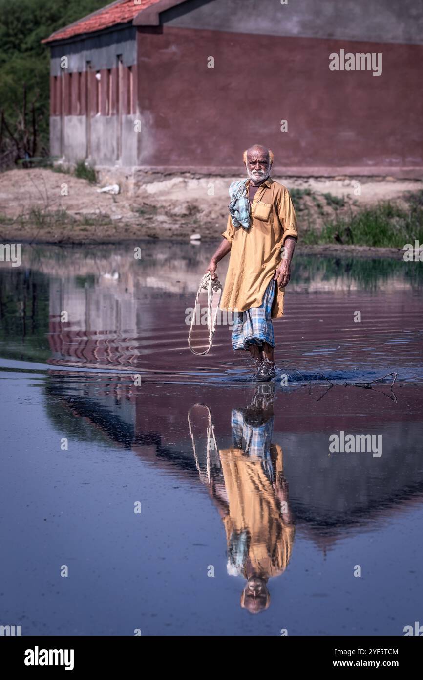A man walking through a flooded area in a village, Kutch region ...