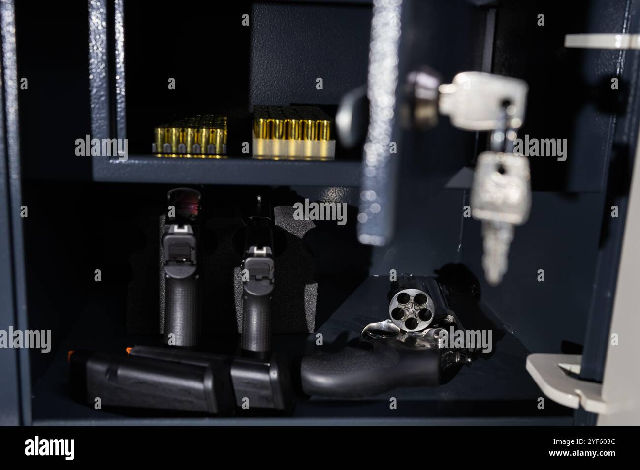 Firearms. Modern pistols, revolver and ammo in a gun safe, close up ...