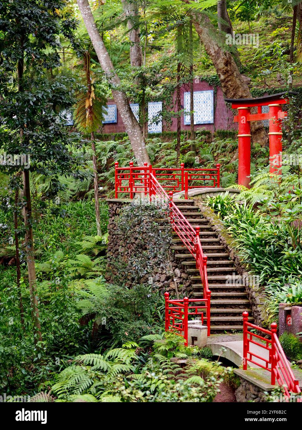 A series of stairs with vibrant red railings leading through lush ...
