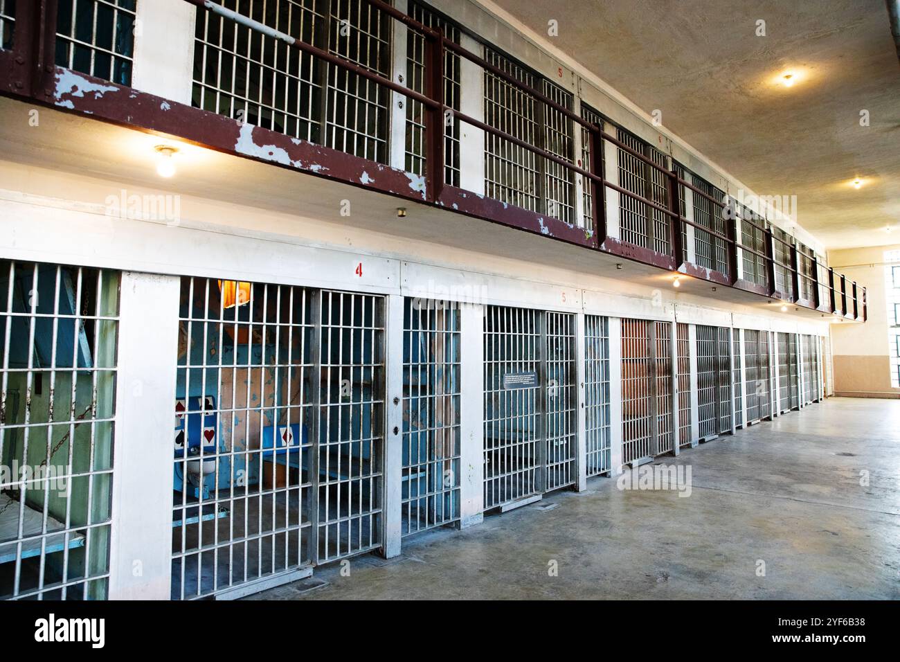 Abandoned Prison Corridor With Metal Cell Doors and Dim Lighting Stock Photo - Alamy