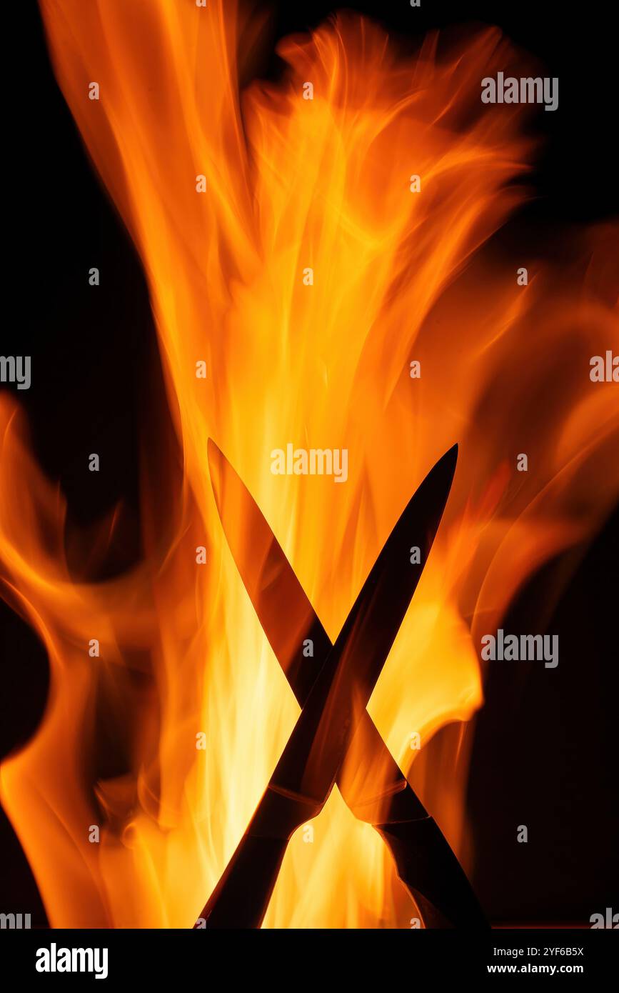 Two crossed knives in tongues of hot flame on a black background Stock ...