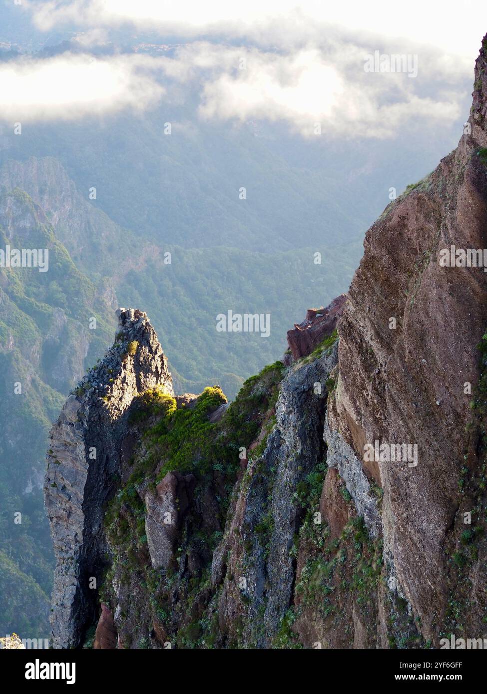 A dramatic mountain peak towers into a sky filled with clouds, creating ...