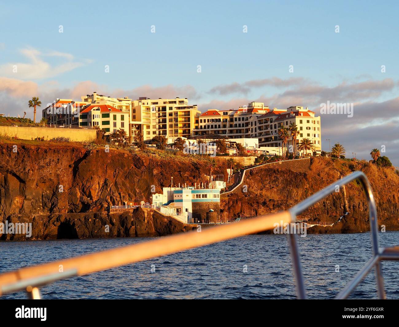 Modern resort architecture graces the sunlit coastal cliffs, blending ...