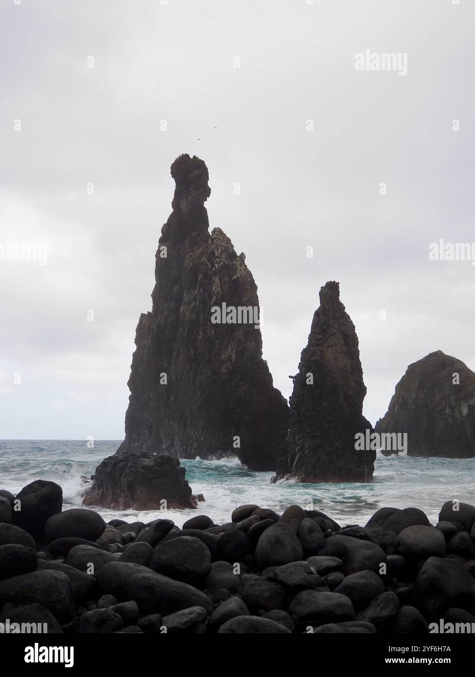 A breathtaking view of three jagged rocks emerging from the ocean, with ...