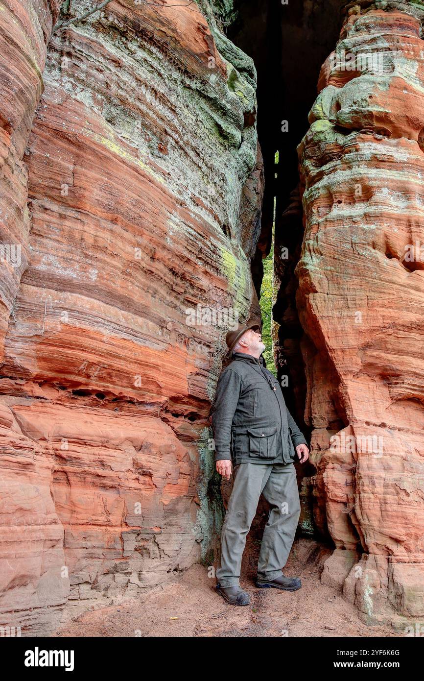A hiker stands in a deep rock crevice at the Altschlossfelsen, admiring ...