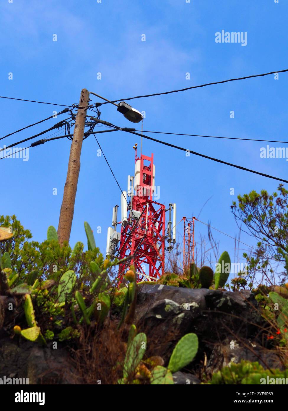 The photo illustrates a red communication tower standing tall against a ...