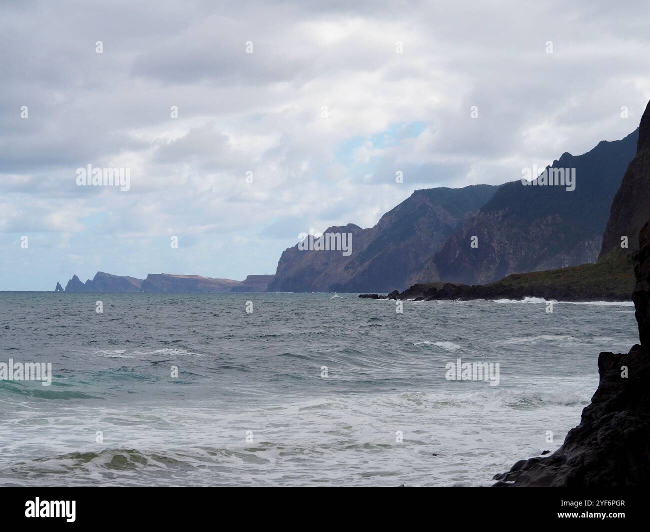 A striking image of a towering rocky cliff face beside the ocean, with ...