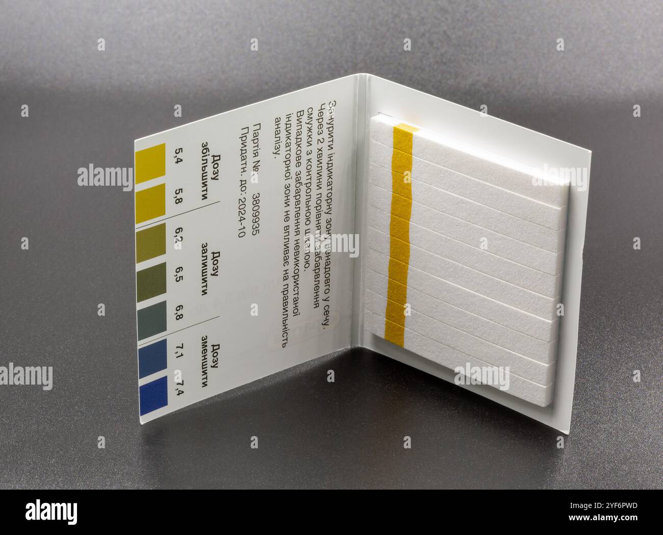 Urine pH diagnostic strips with scale closeup on black. Scale by which ...