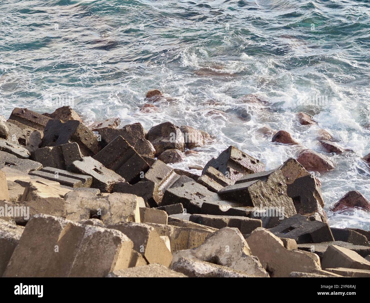 The rugged coastal line features hexagonal concrete blocks strewn ...