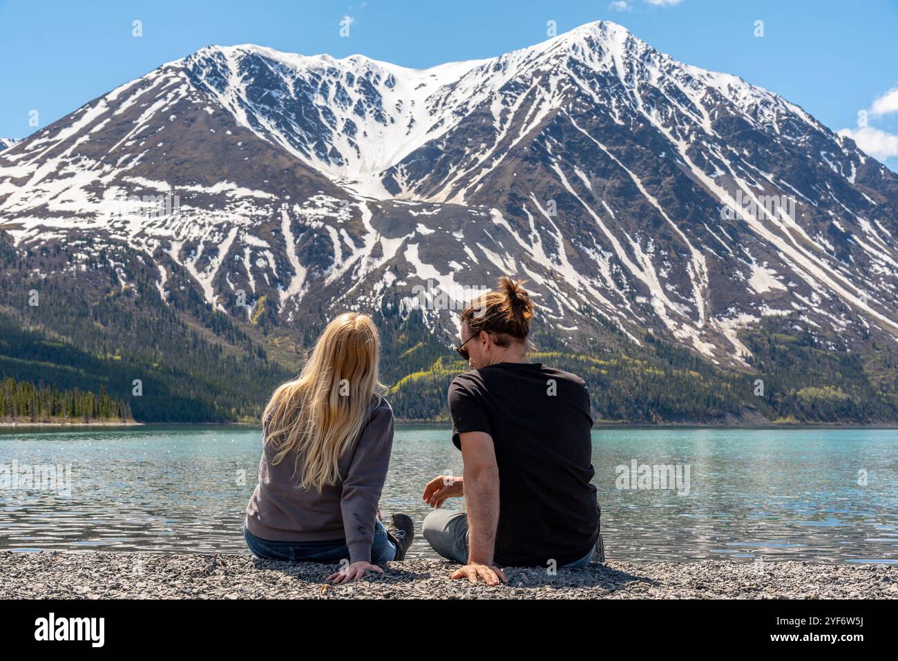 Two people, friends, couple sitting on camping chairs with picnic table ...