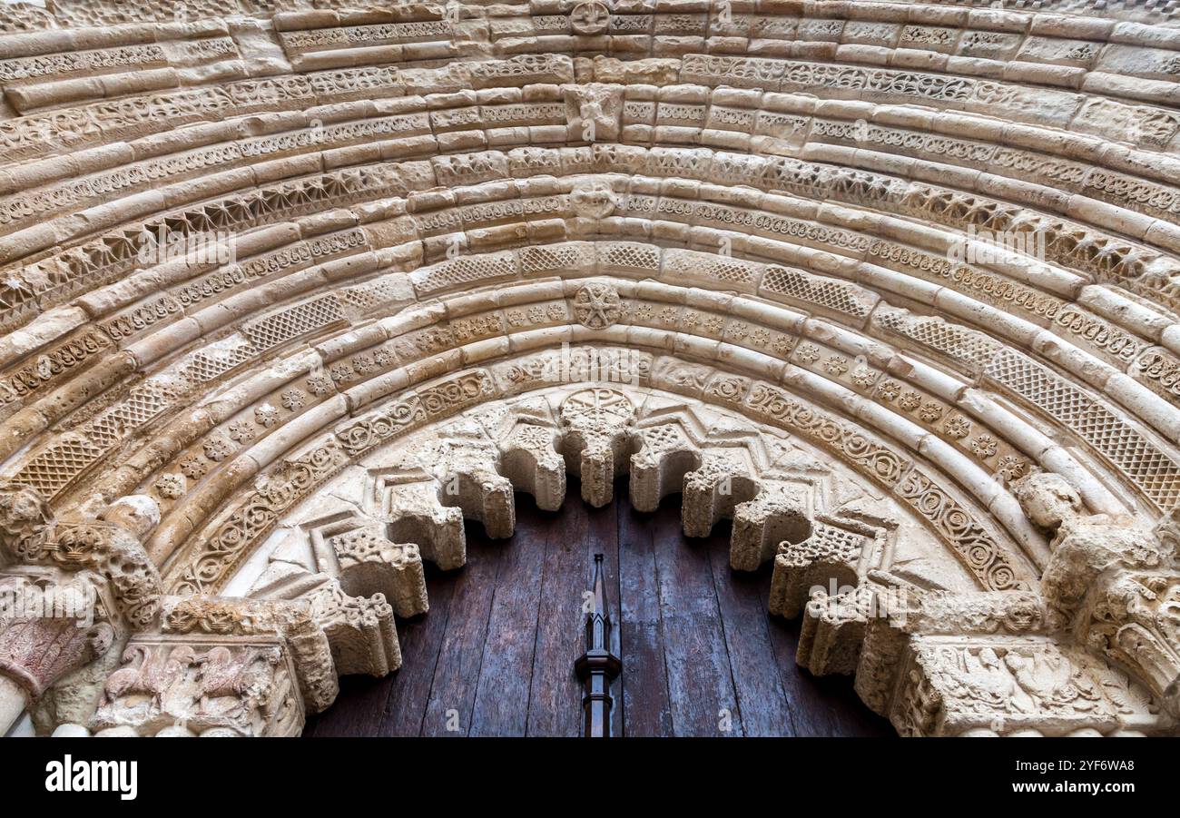 A beautifully carved stone archway frames the large wooden doors of an ...
