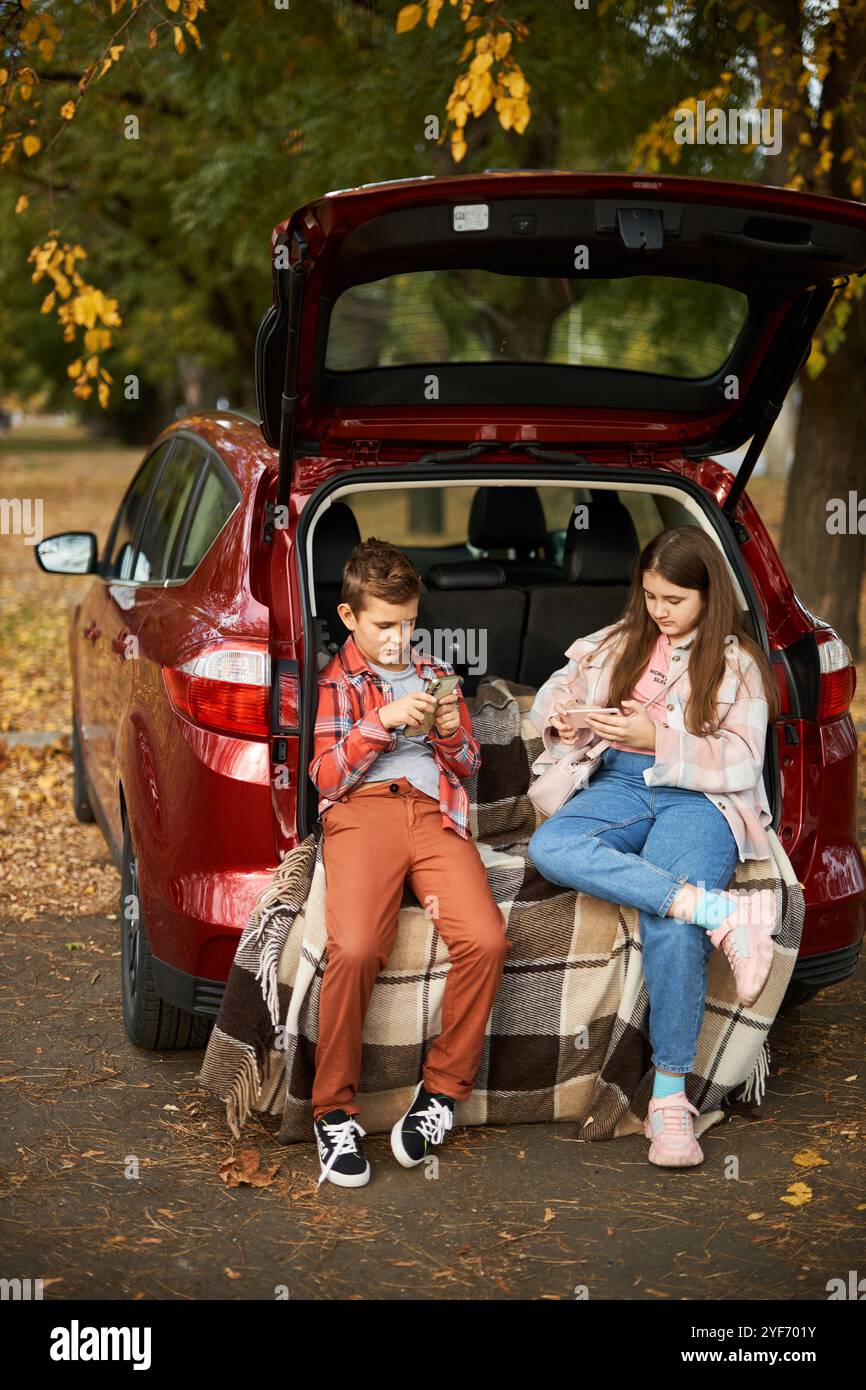 Two children sit in the trunk of a car and use smartphones Stock Photo ...