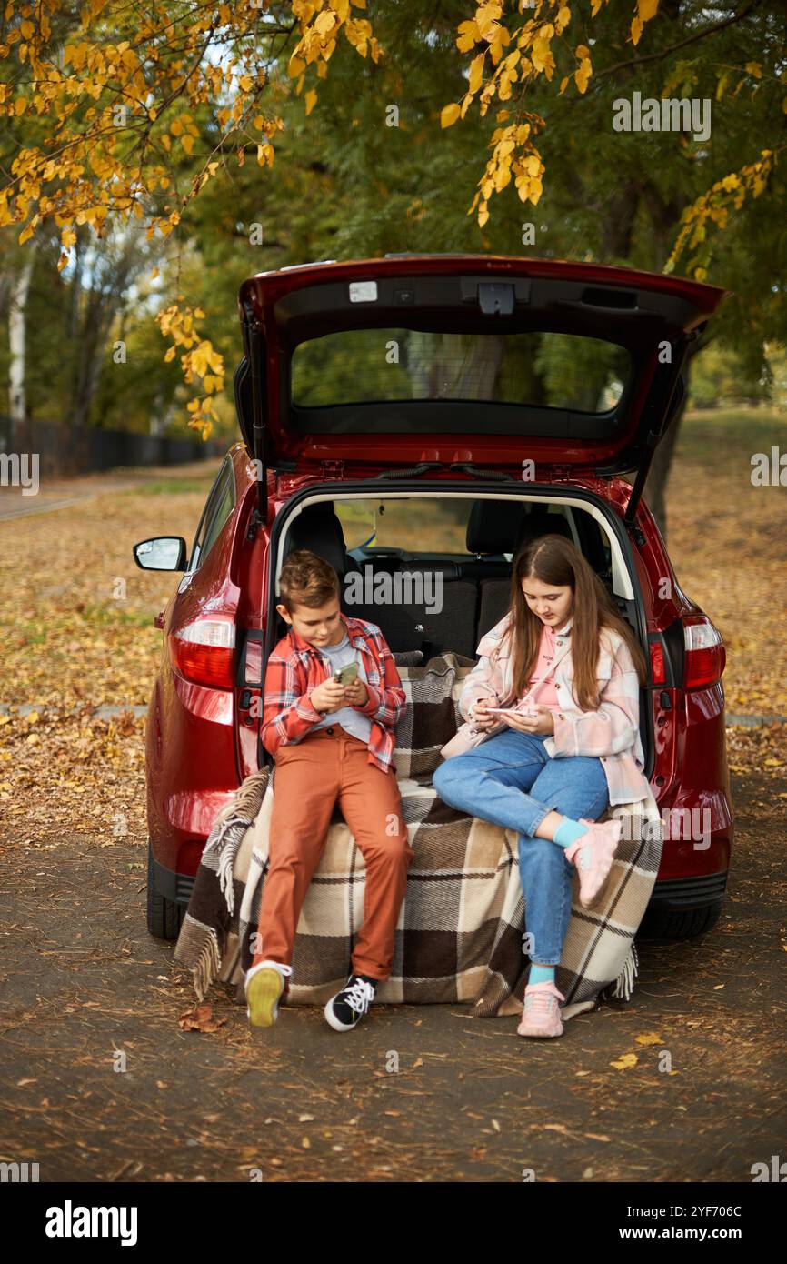 Two children sit in the trunk of a car and use smartphones Stock Photo ...