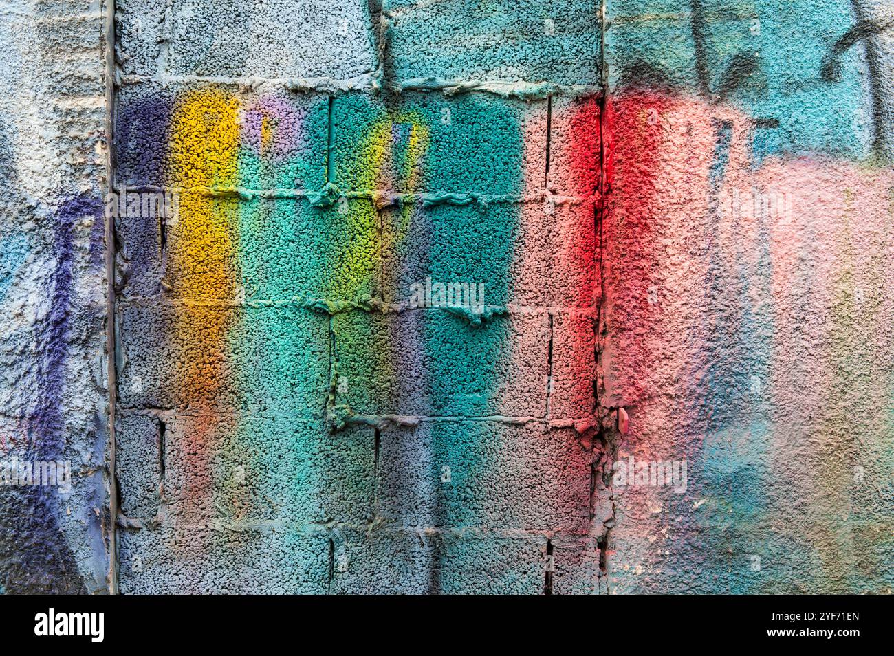 Colorful, painted yellow, blue and red cinderblock wall in an alley in ...