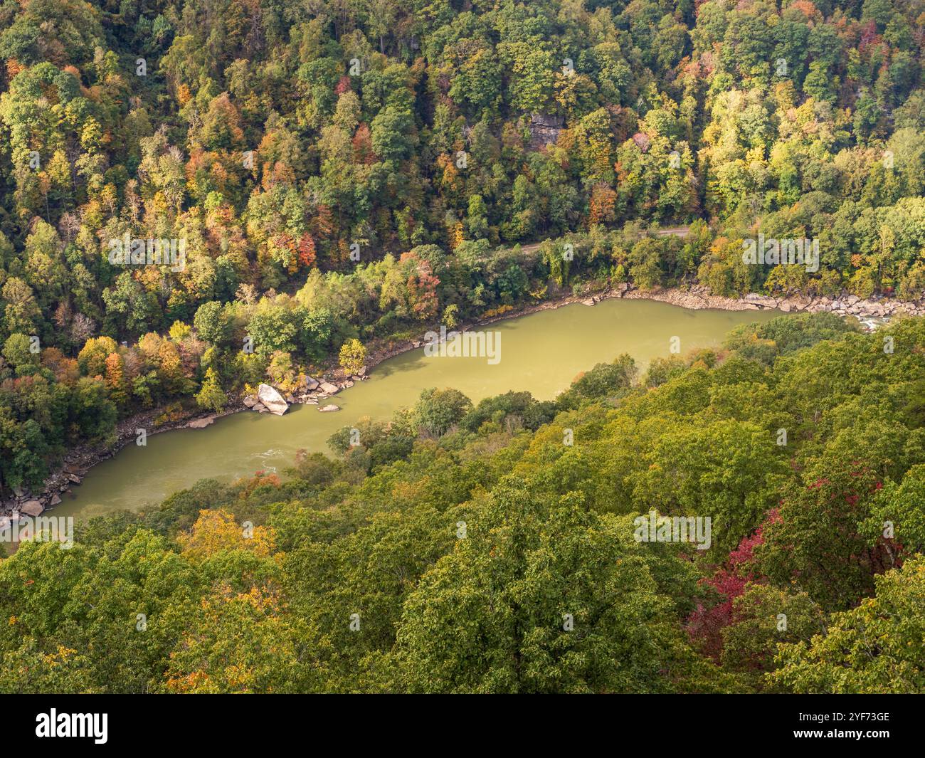 Sunlight highlights the fall-colored mountainside above the water at ...