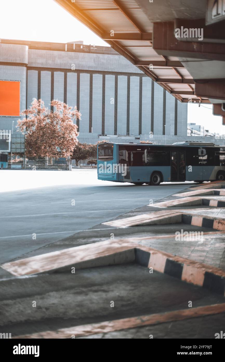 A vertical shot of a modern city bus station with a blue bus parked ...