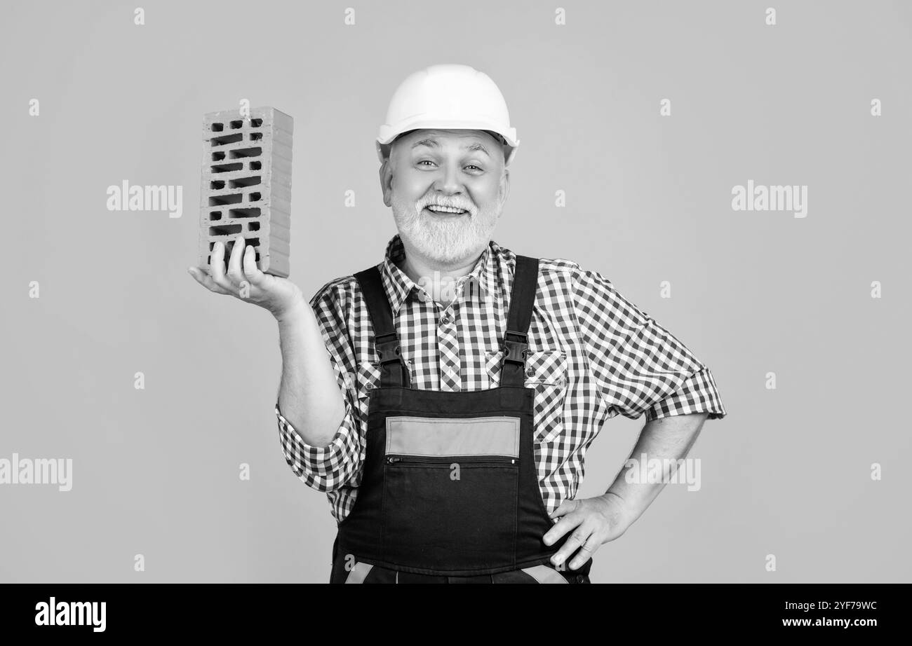 happy aged man bricklayer in helmet on yellow background Stock Photo ...