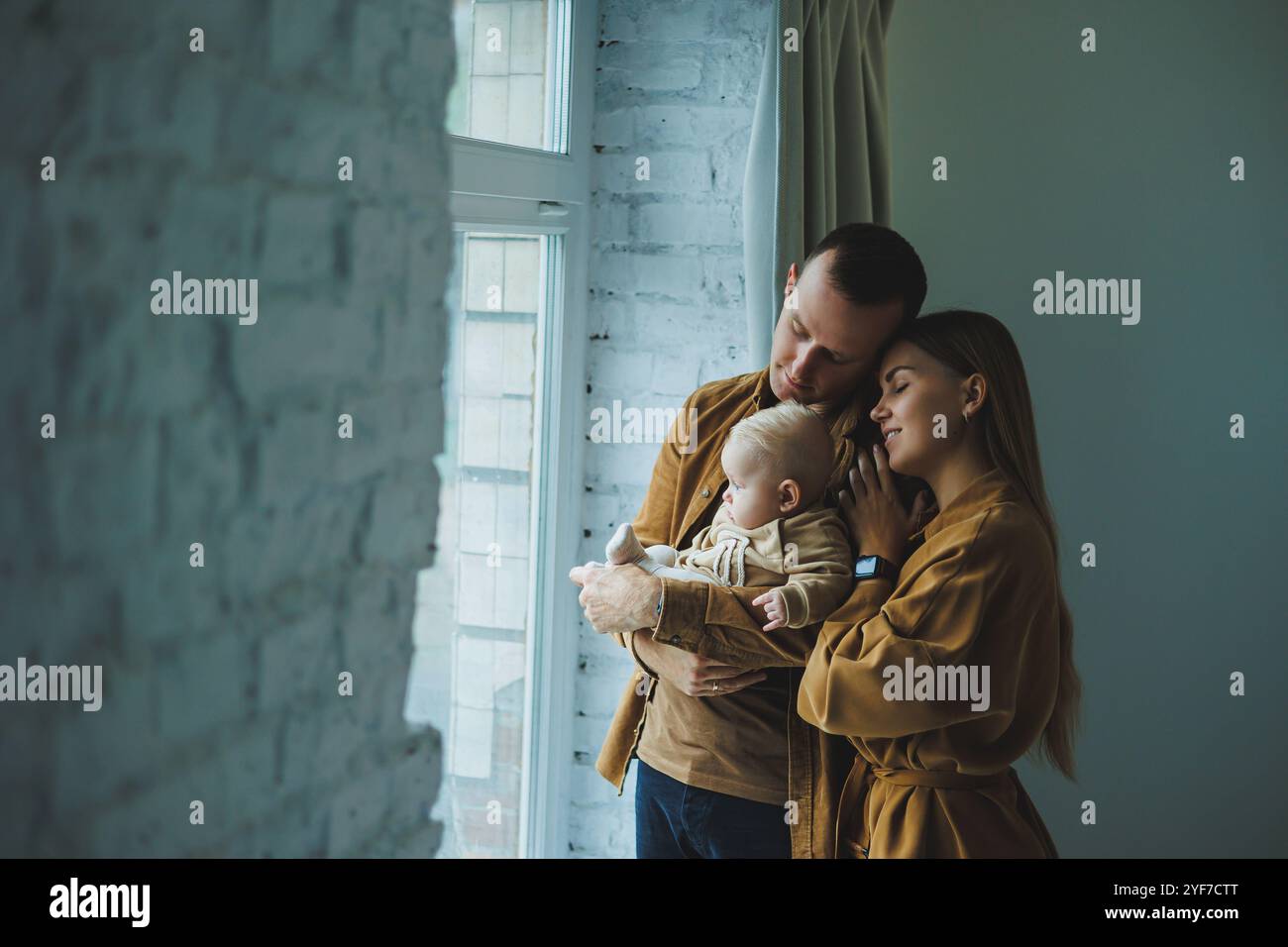 A happy mother and father hold their 4-month-old son in their arms and ...