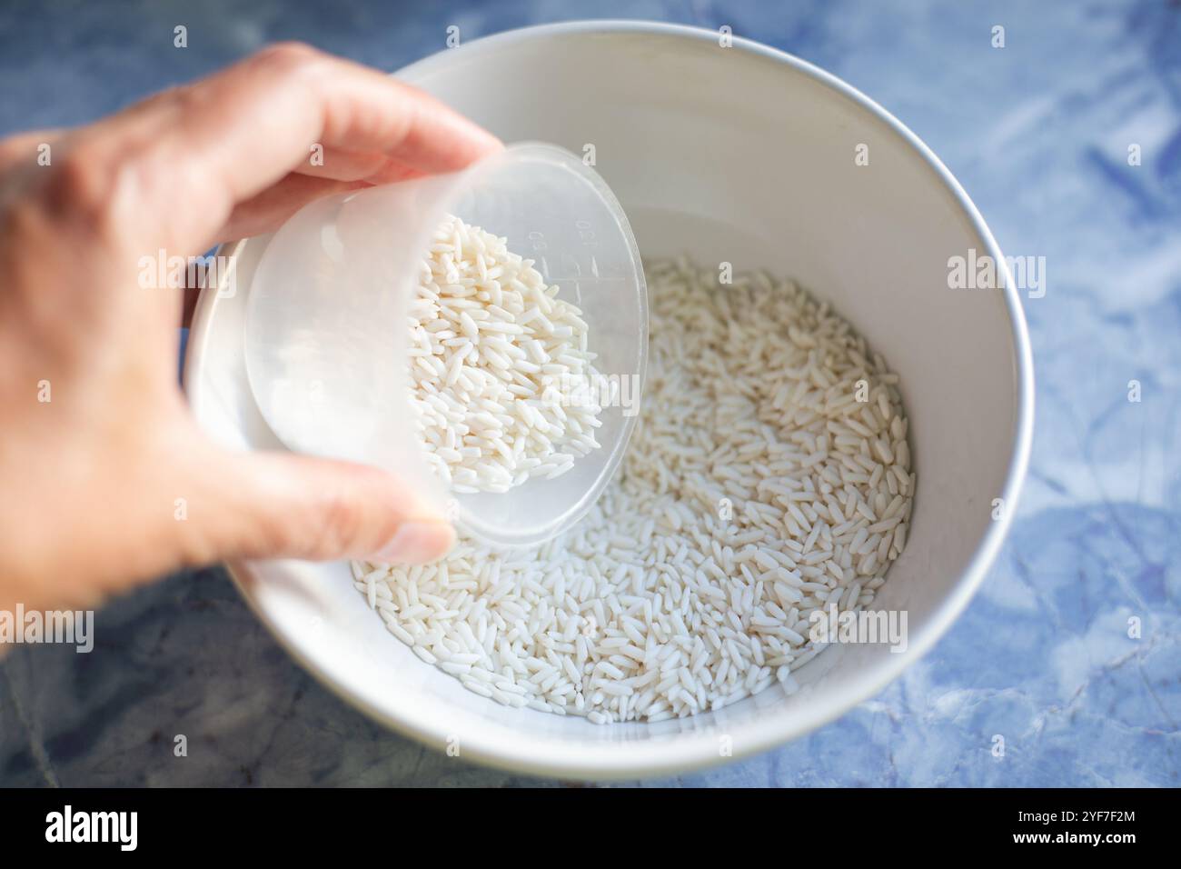 Cooking rice. The woman measures out a glass of rice and pours it into ...
