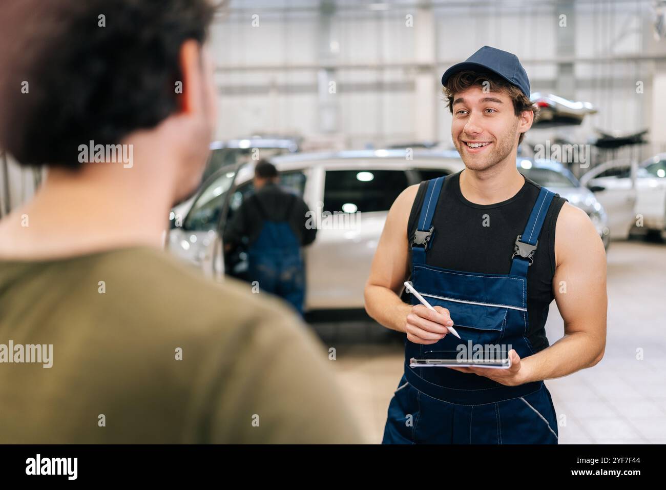 Positive mechanic male in uniform explaining checklist car maintenance ...