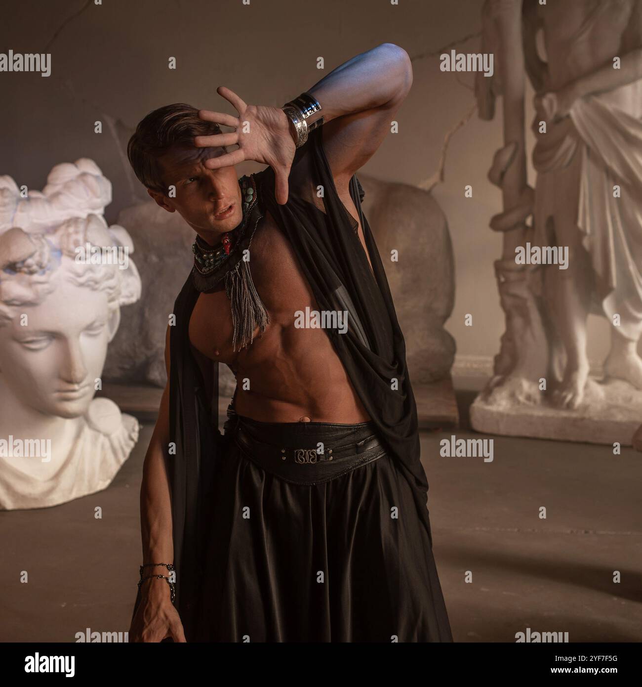 Muscular charismatic bodybuilder model in a silk cape makes an ...