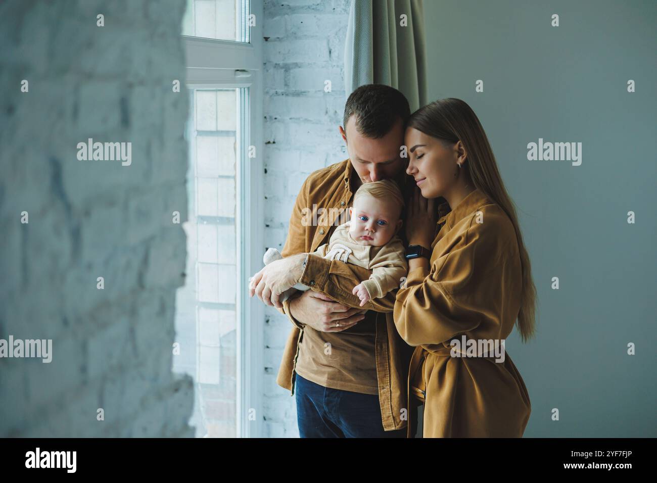 A happy mother and father hold their 4-month-old son in their arms and ...