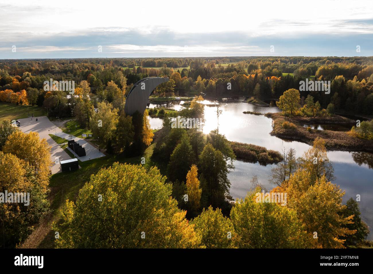 A curved observation tower rises above vibrant autumn trees, with a ...