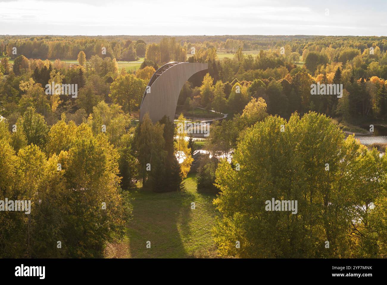 A modern curved observation tower stands amidst a vibrant autumn ...
