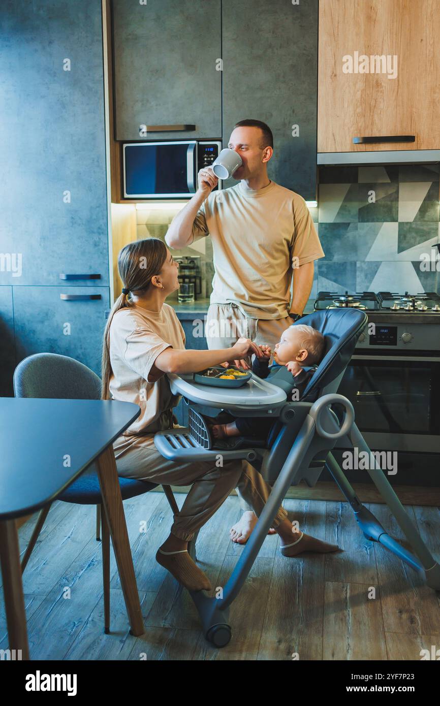 The first complementary food for the baby with a spoon. A mother feeds ...