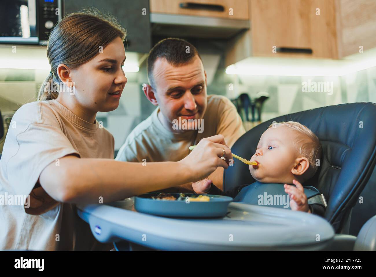 The first complementary food for the baby with a spoon. A mother feeds ...
