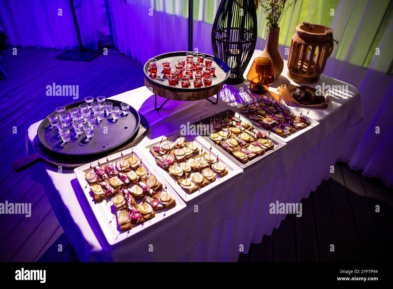A buffet table features canapes on platters and drinks in small glasses ...