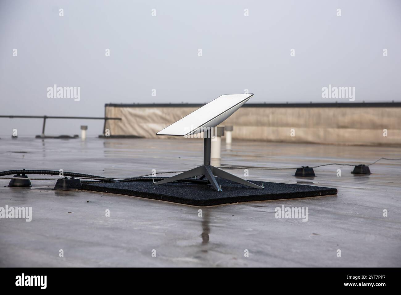 A Starlink satellite dish is installed on a flat rooftop, mounted on a ...