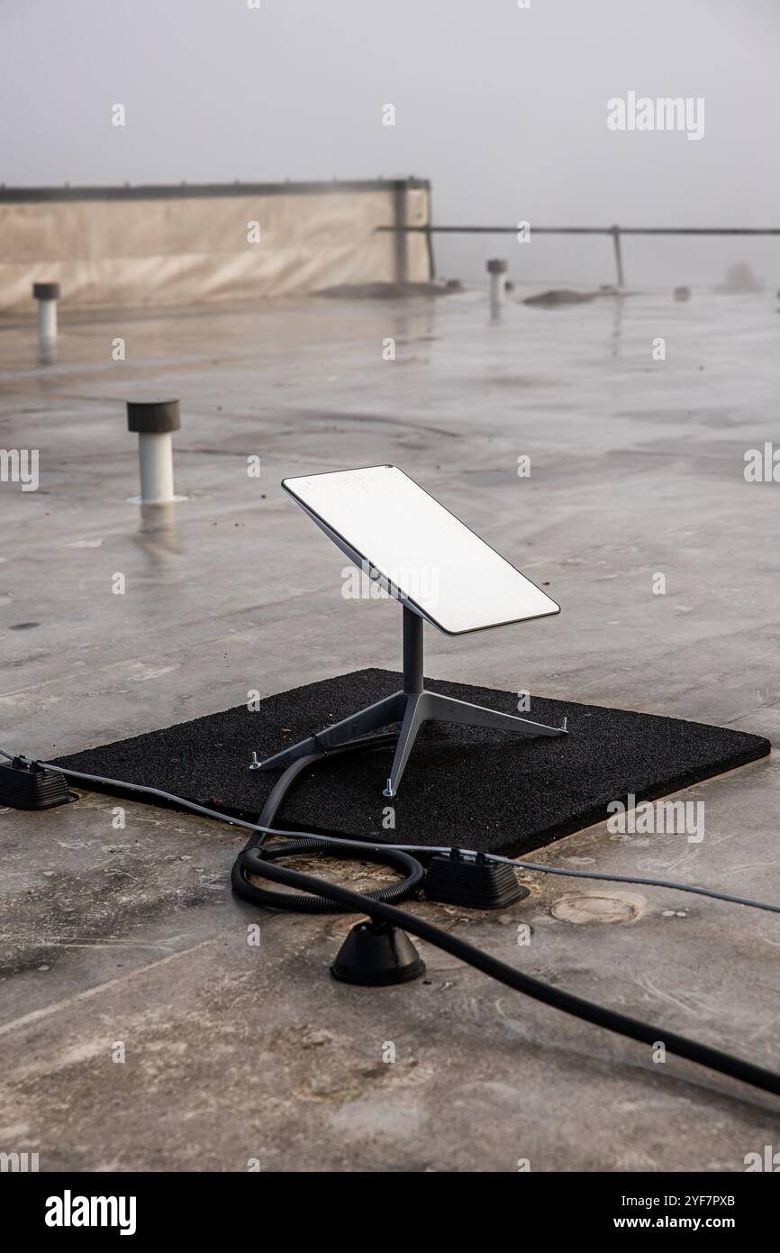 A Starlink satellite dish is installed on a concrete rooftop ...