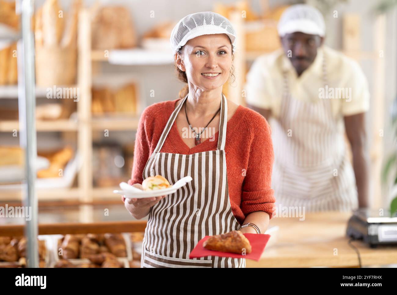 Cheerful woman baker with pastries in bakery Stock Photo - Alamy