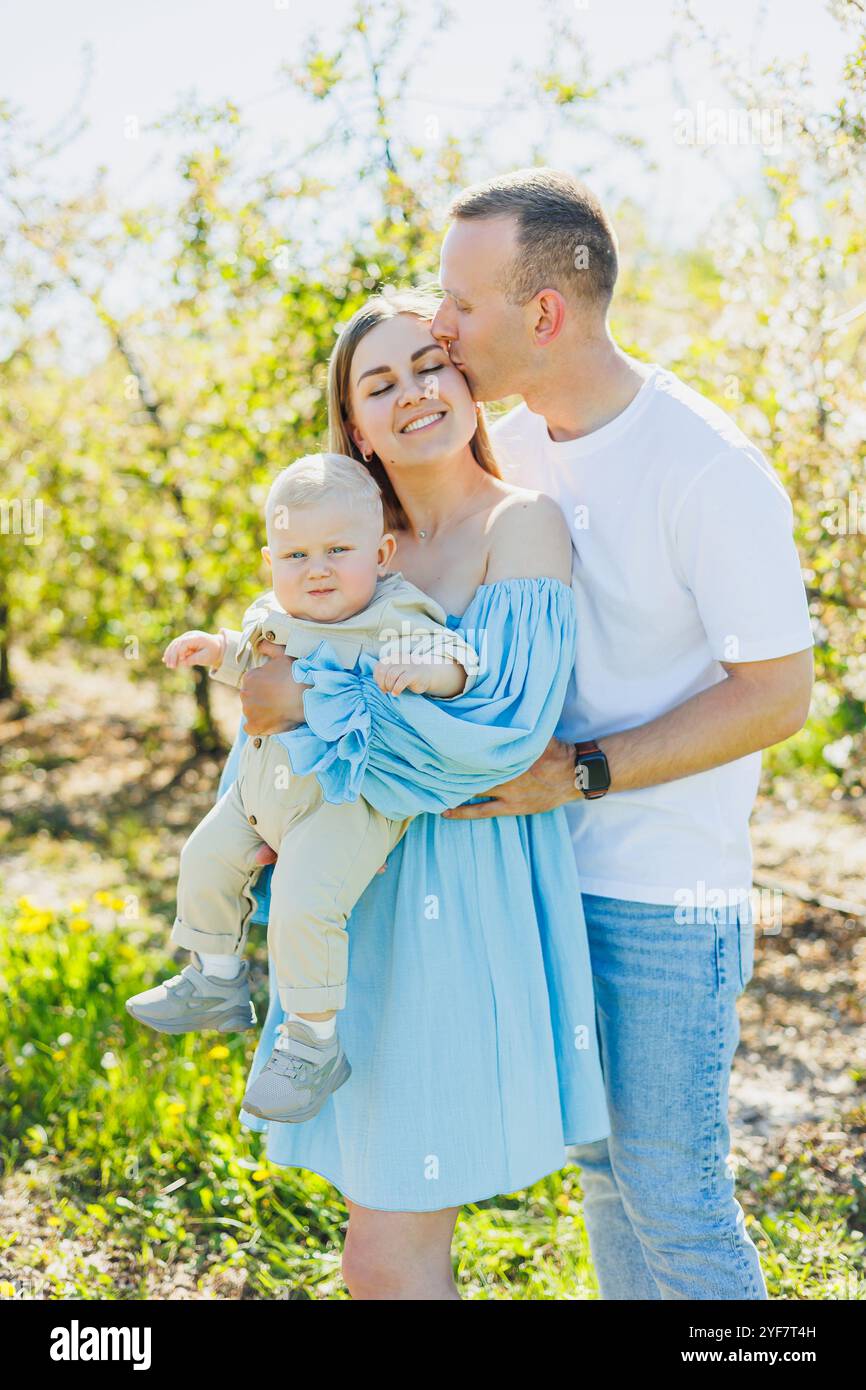 A young married couple with a small son in a blooming garden. A happy ...